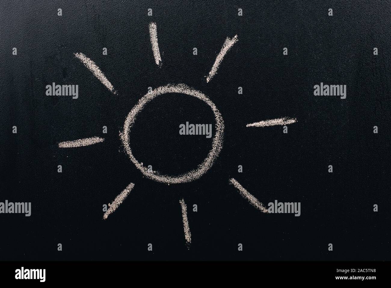 Hand drew sun by chalk with light ray shape on blackboard background ...