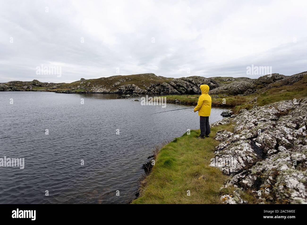 Young boy fishing on the shore of coastal landscape on Lettermullan ...