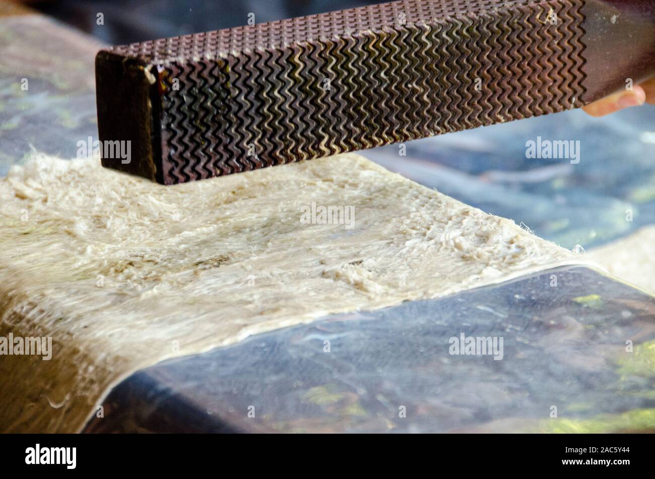 A close-up of Roen Hufford using a wooden beater to make kapa (or tapa ...