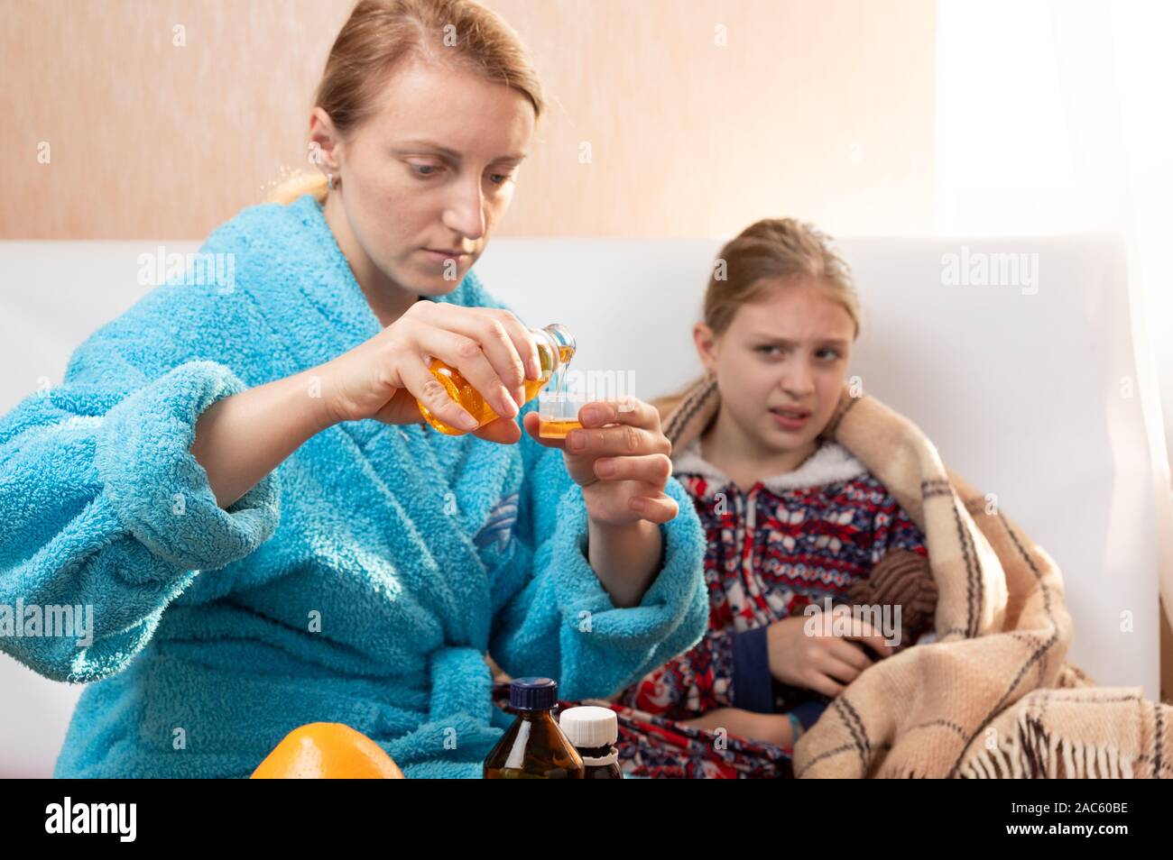 Mom pours cough syrup. Mom treats her daughter. Home treatment Stock ...
