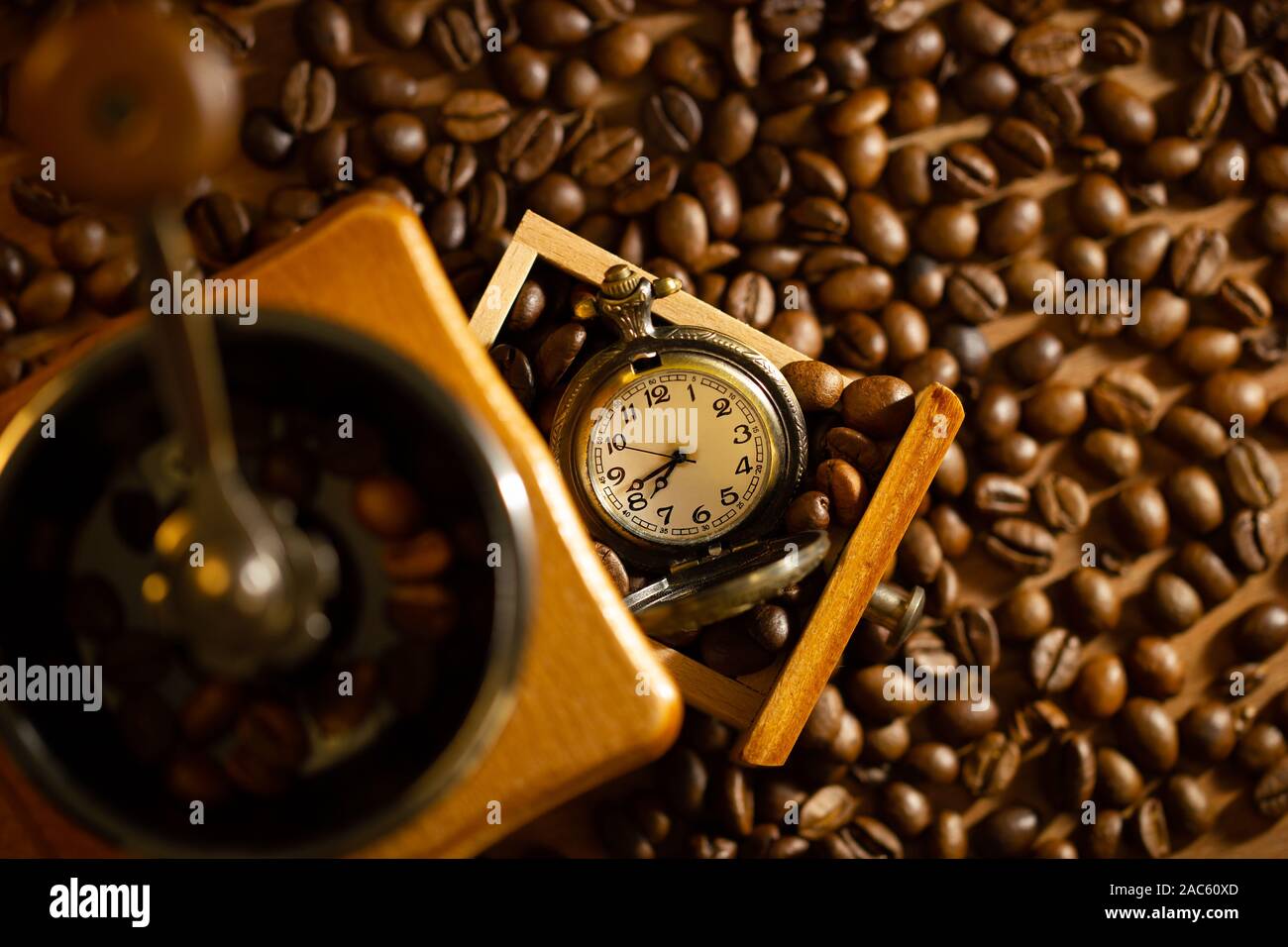 Coffee bean and pocket watch the tray of manual grinder on table. Top ...