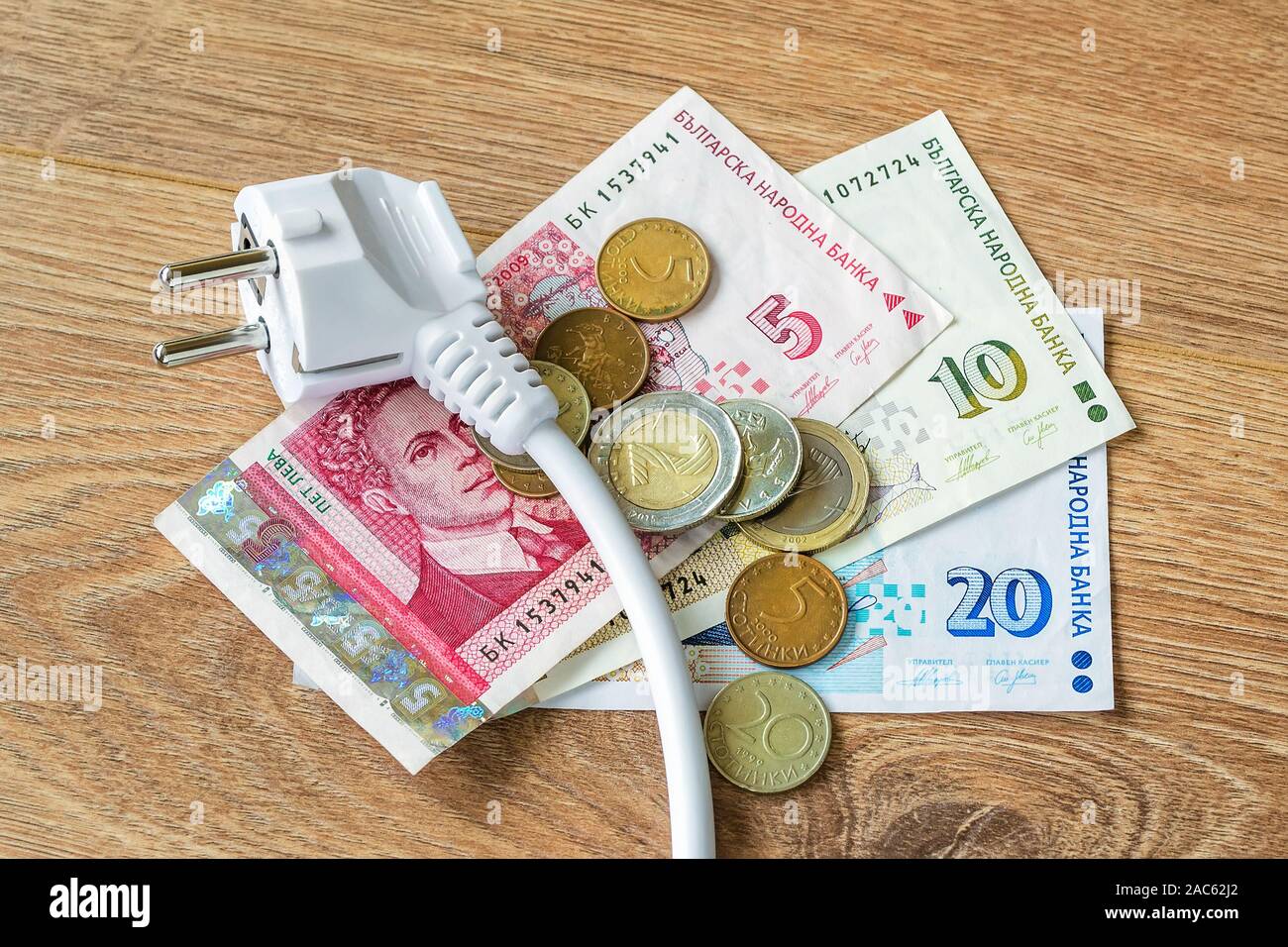 White power plug on bulgarian leva banknotes and coins over a brown ...