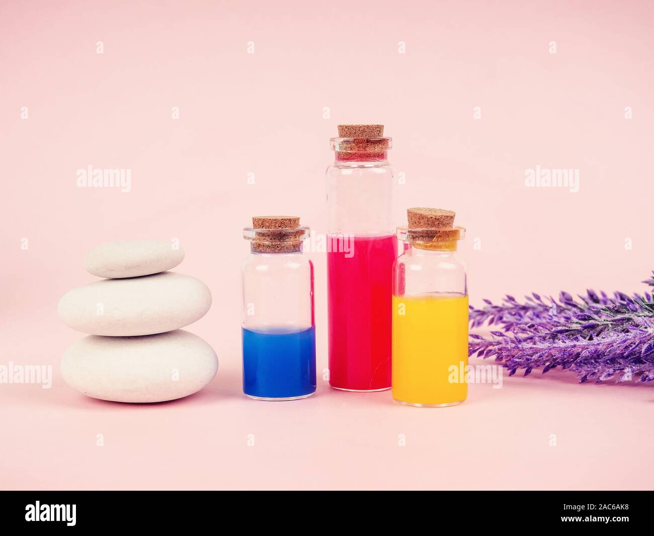 Flowers and plant extracts or perfume in small bottles on pink ...