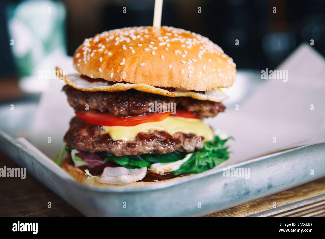 Big burger on restaurant table, close-up, focus on the bun, toned image ...