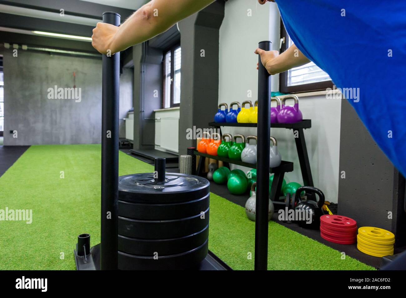 Young female fitness trainer performing sled push in local gym Stock ...