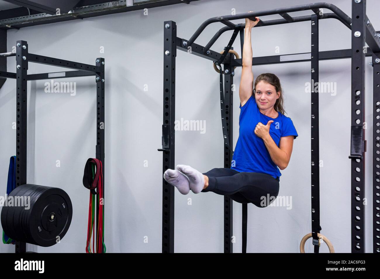 Active brunette having fun on pullup rig doing one hand leg-raises ...