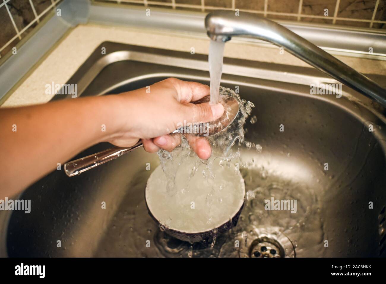 hand washing spoon under the tap in the sink. the plate is blurred ...