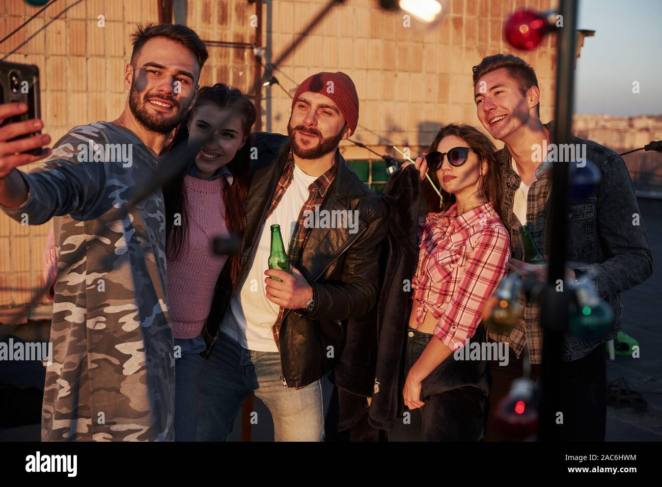 Selfie time for group of positive friends stands on the rooftop with ...
