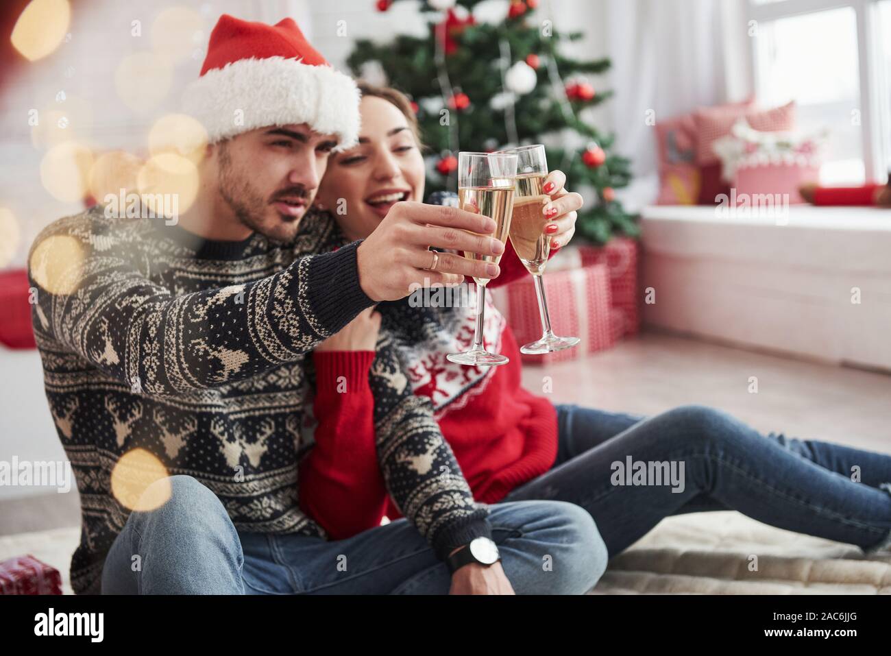 Making a toast. Two people sits on the floor and celebrate new year ...