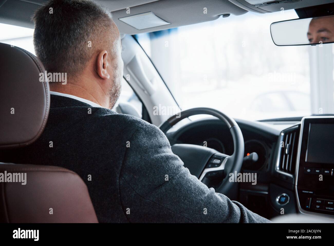 Reflection of face in the front mirror. View from behind of senior ...