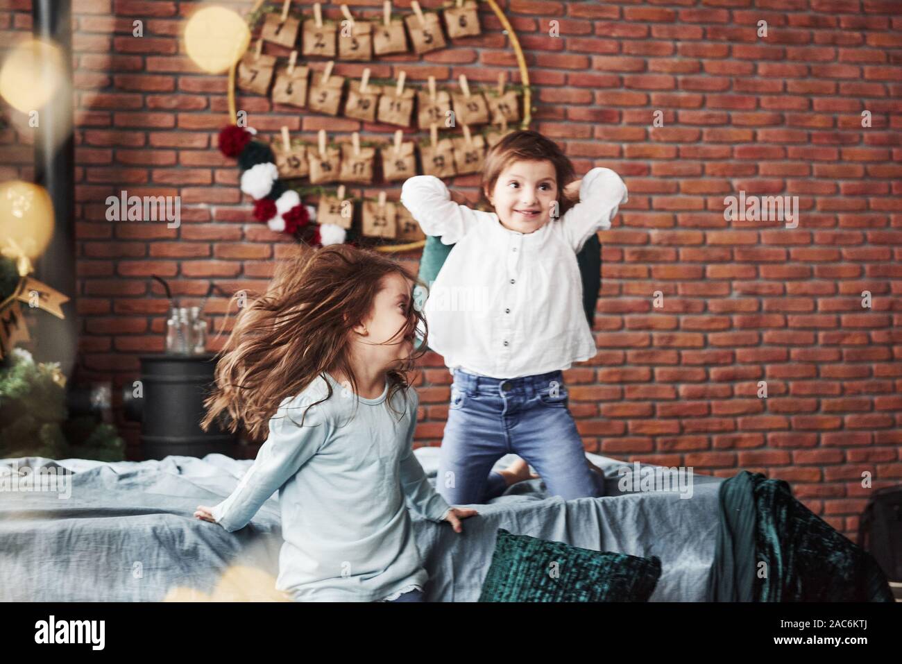 Kid jumping off the sofa. Little girls having fun on the bed with ...