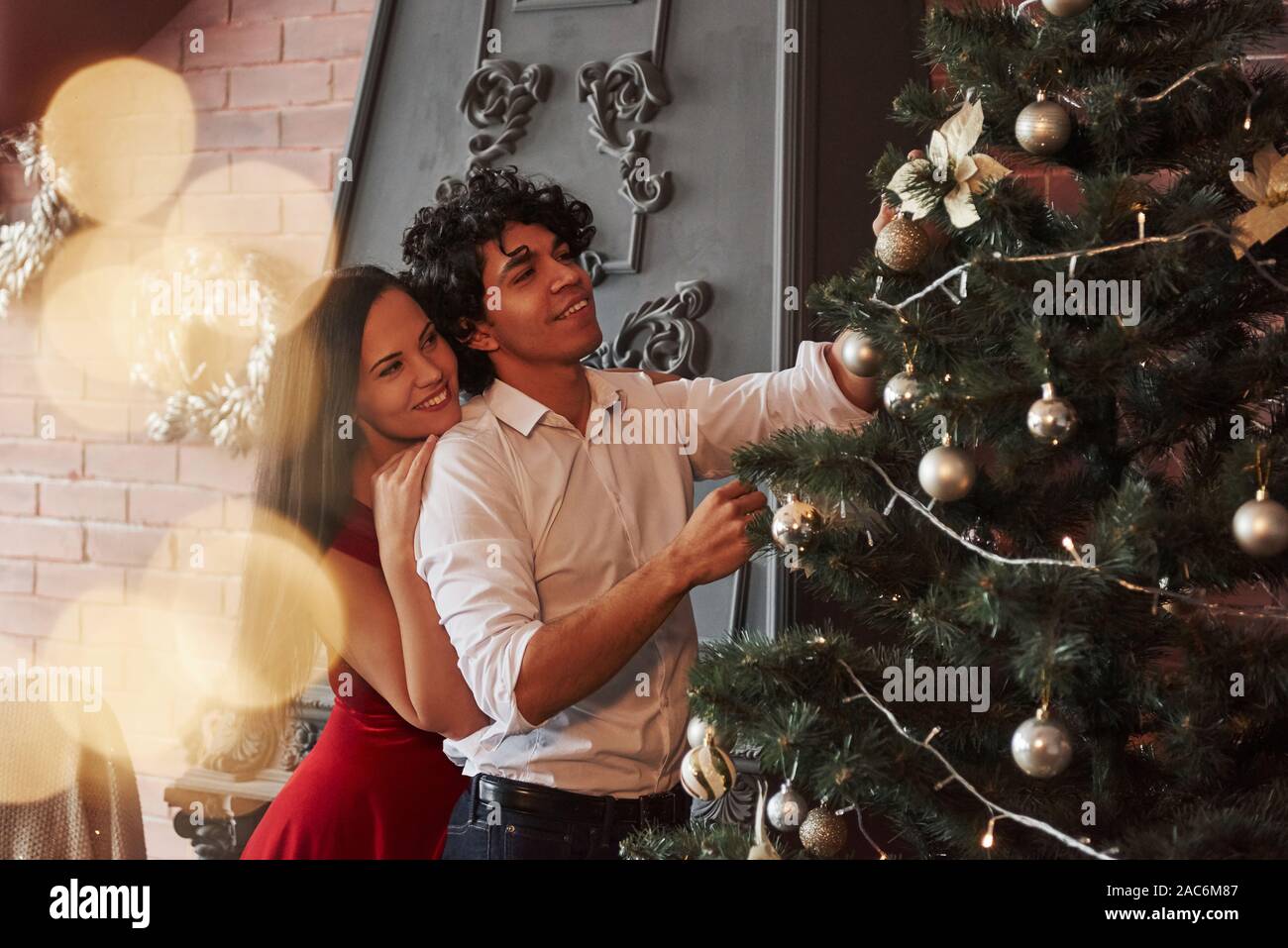 Classic decorations. Romantic couple dressing up Christmas tree in the ...