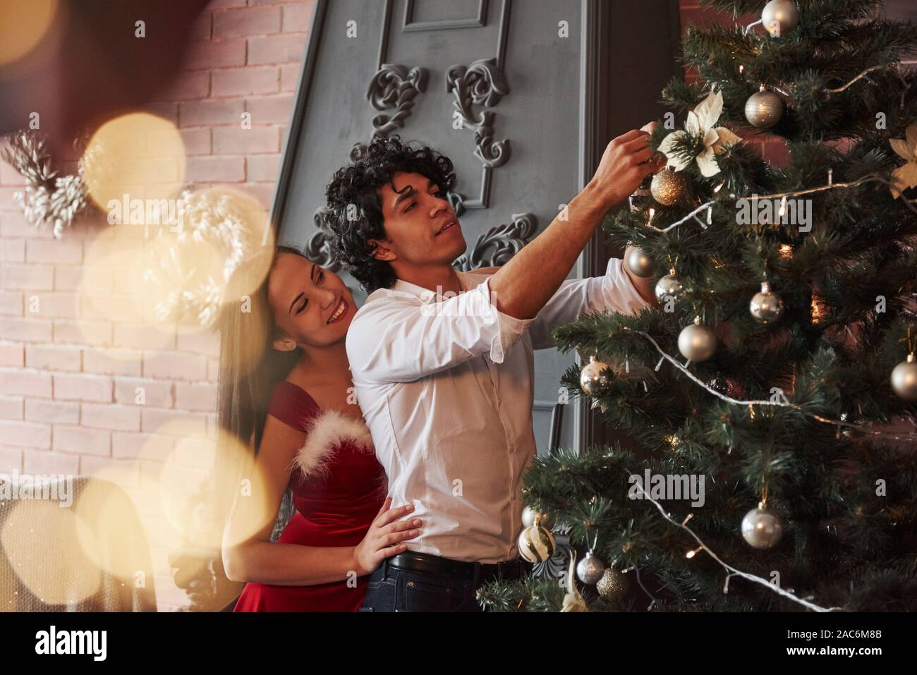 Creating the holiday mood. Romantic couple dressing up Christmas tree ...