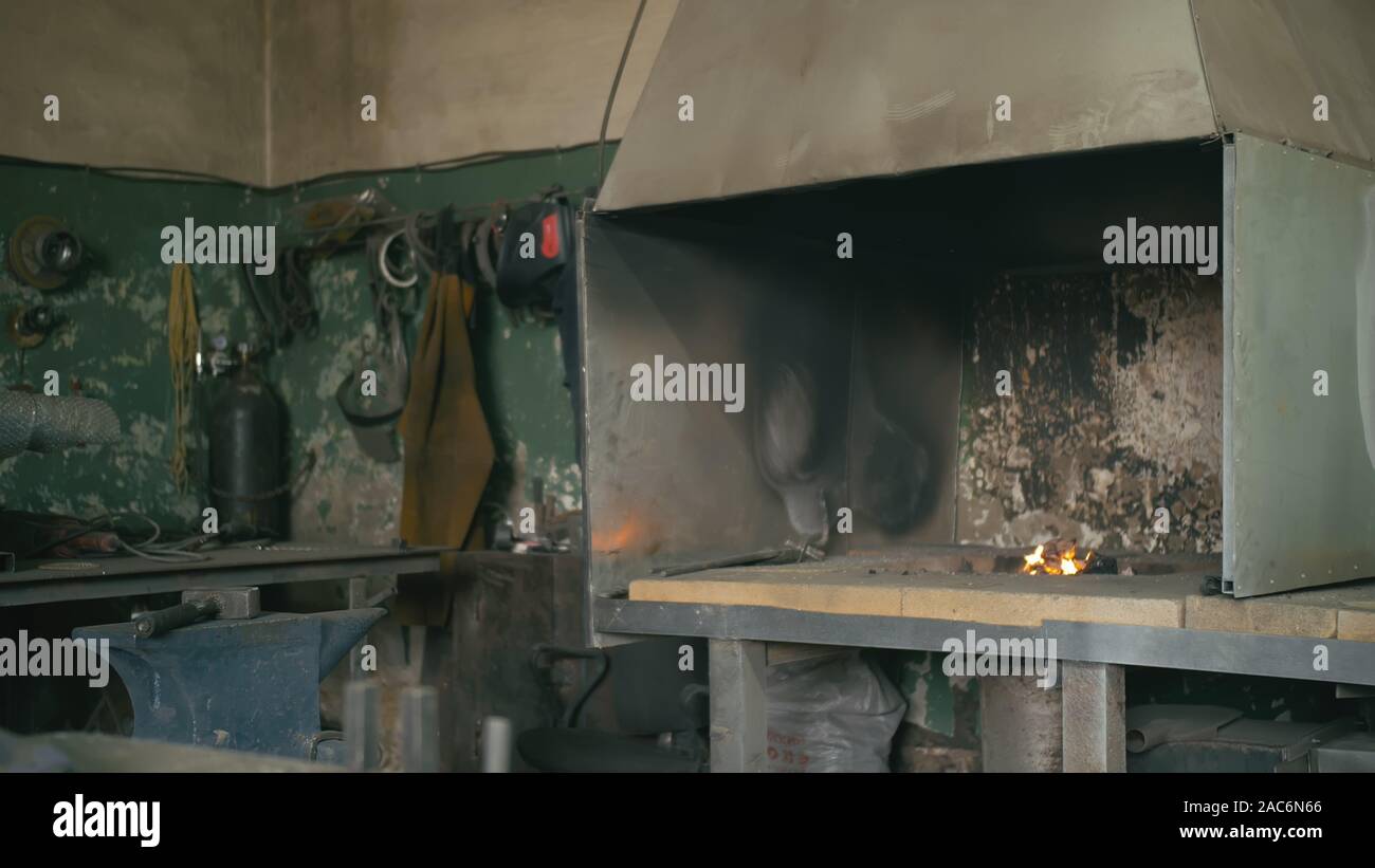 Forge fire in furnace. Blacksmith tempers a steel product in a stove ...