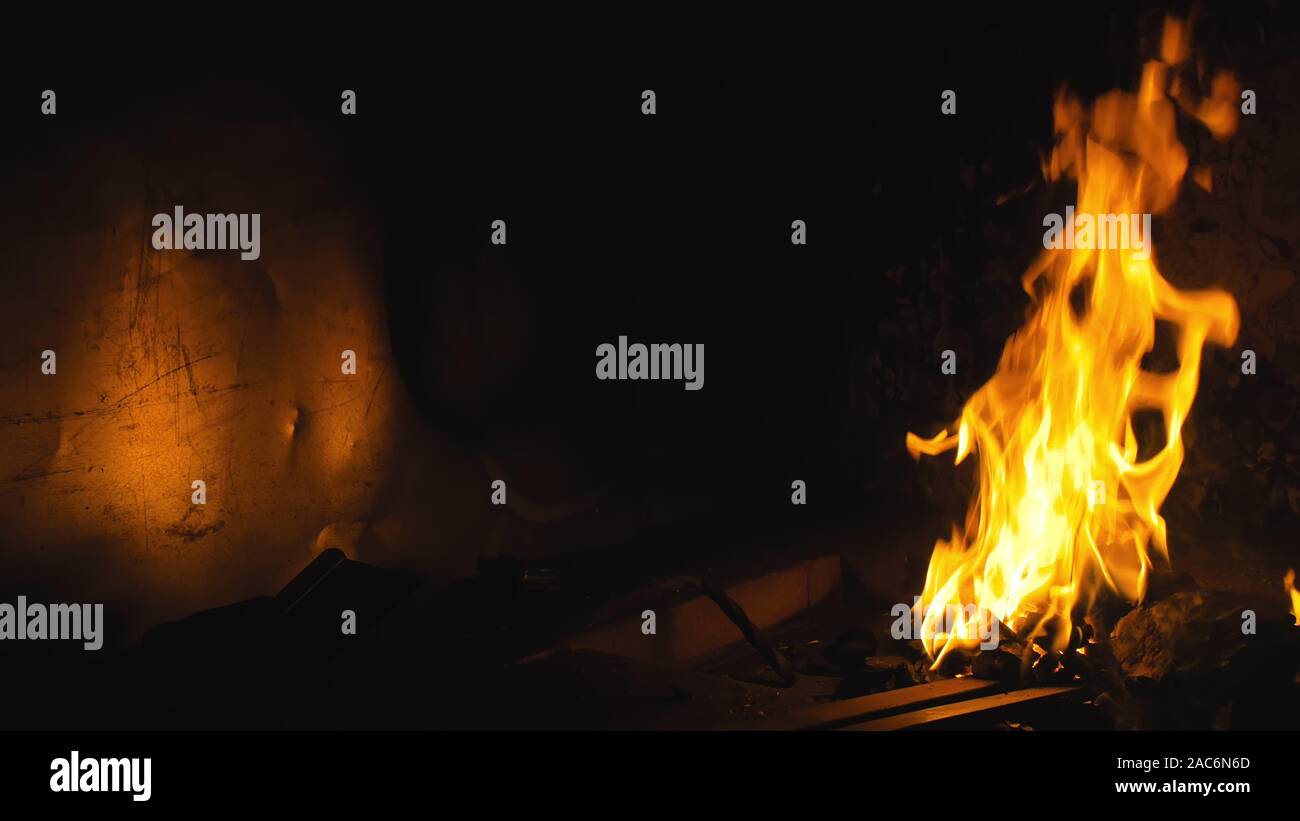 Forge fire in furnace. Blacksmith tempers a steel product in a stove ...