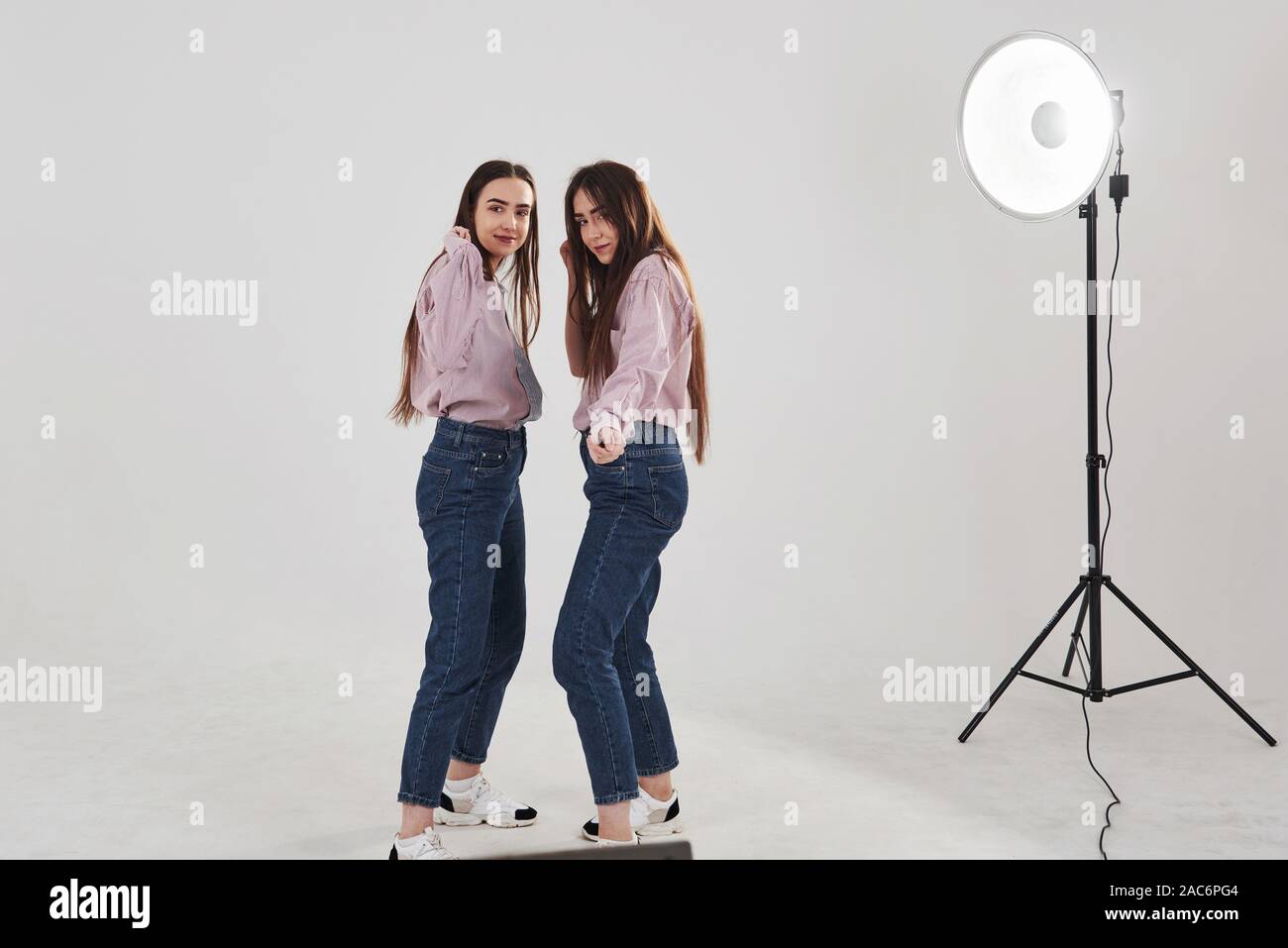 Professional lighting. Two sisters twins standing and posing in the ...