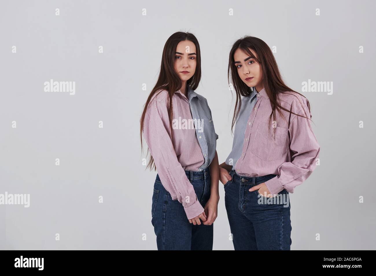 Two sisters twins standing and posing in the studio with white ...