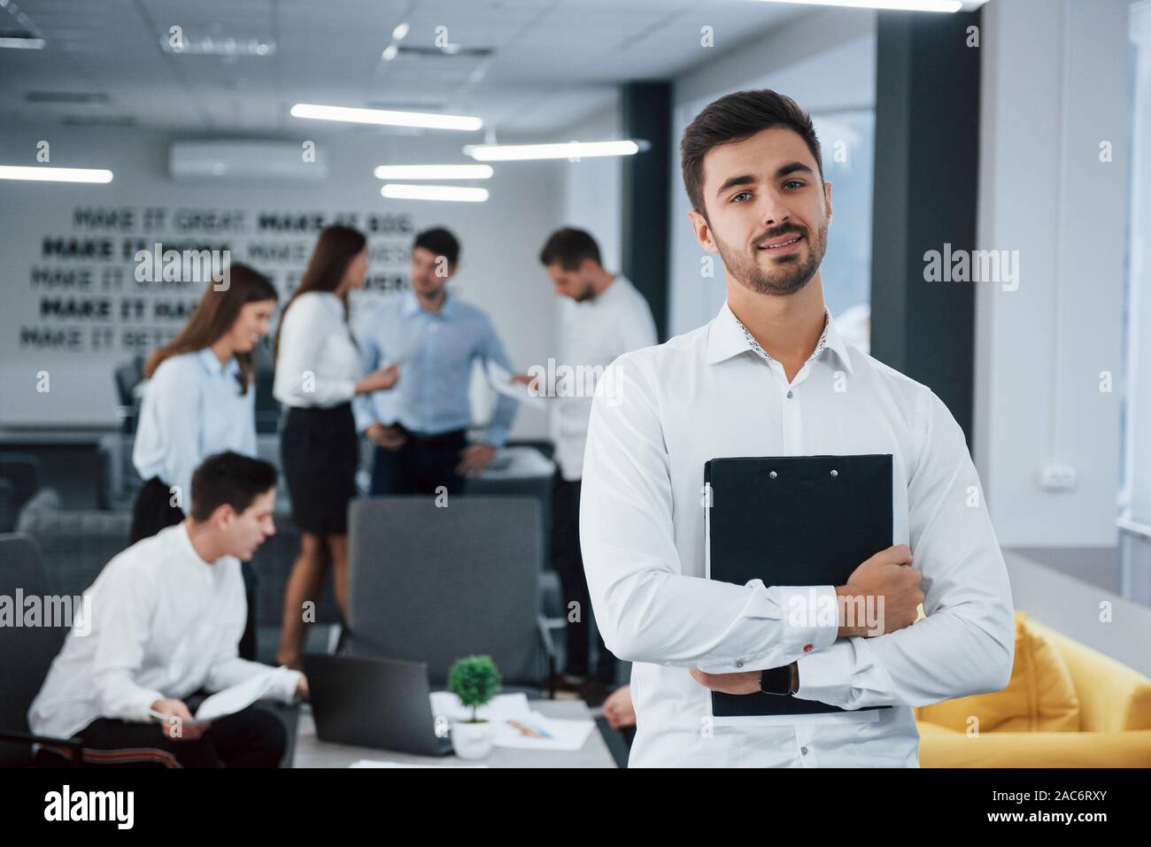 Holding important papers. Portrait of young guy stands in the office ...
