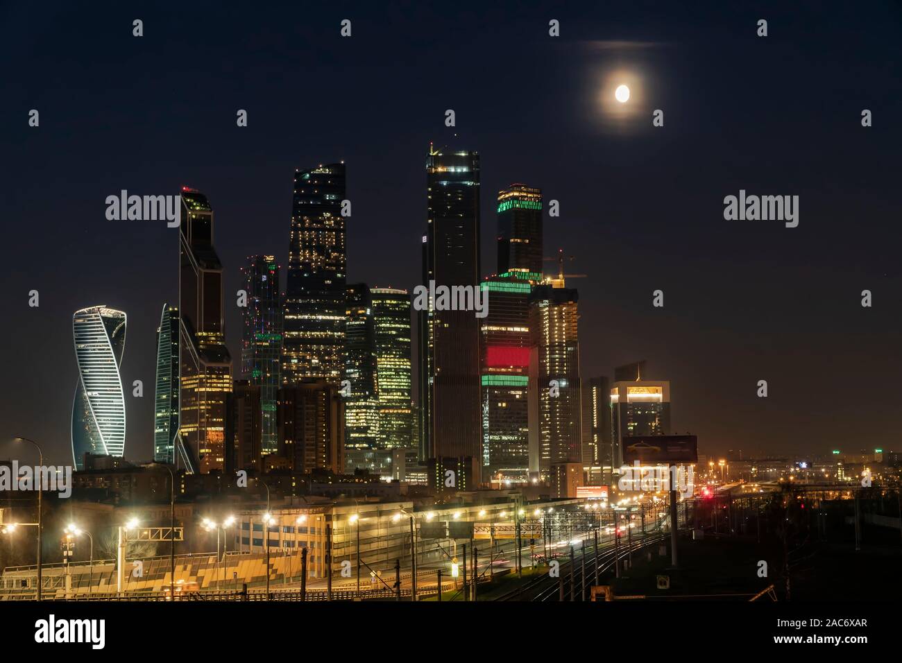 The moon rising over the illuminated highway and the night city Stock ...