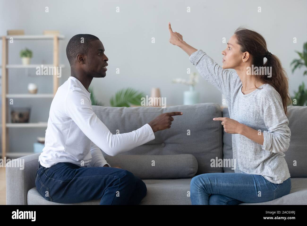 Aggressive mixed race family couple arguing on couch Stock Photo - Alamy