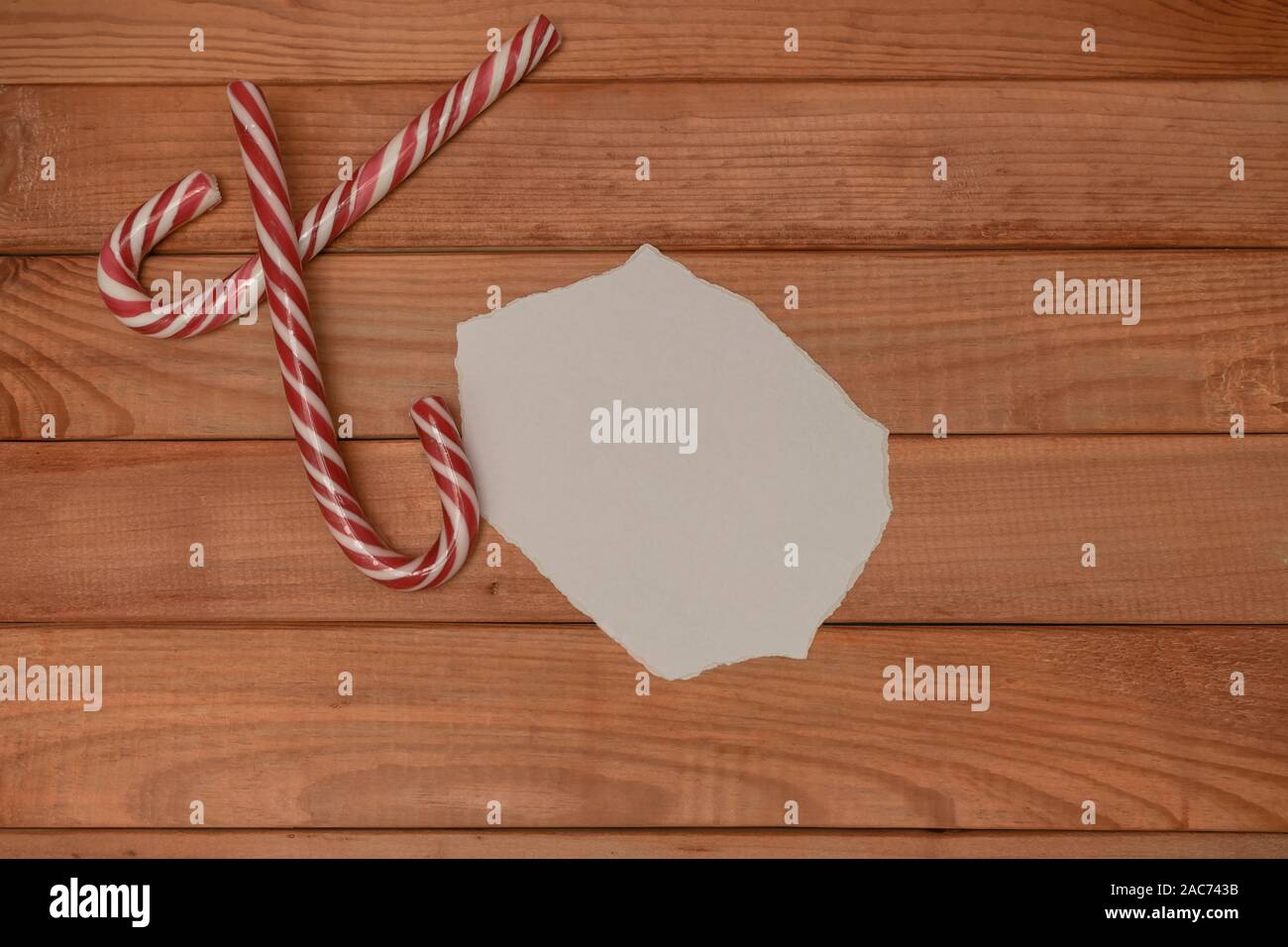Beautiful striped hard candy cane staff on a red wooden table ...