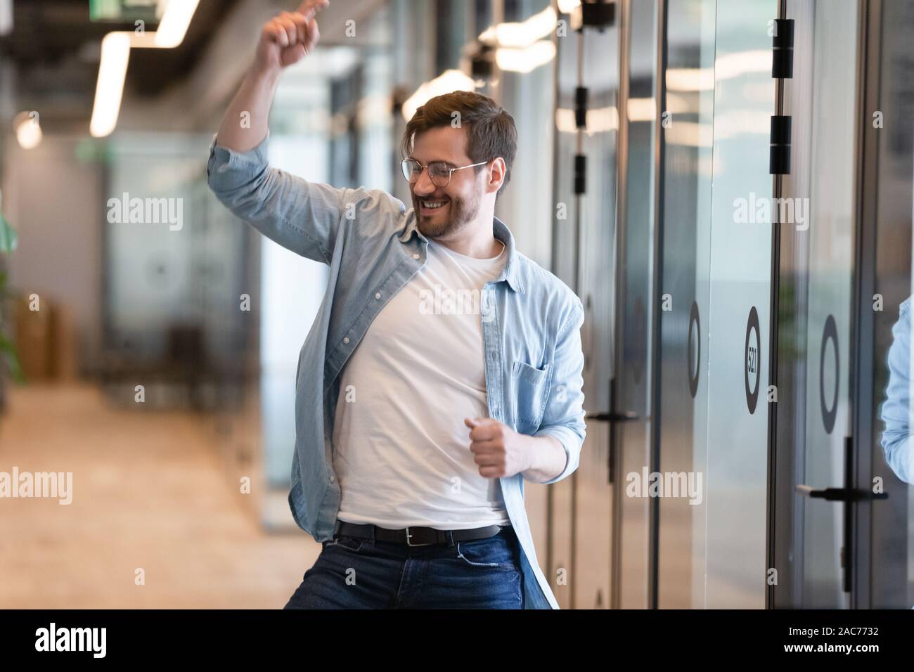 Funny male worker dancing in modern office hallway feels overjoyed ...