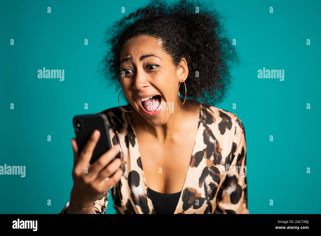 Angry trendy african woman screaming down her mobile phone in studio ...