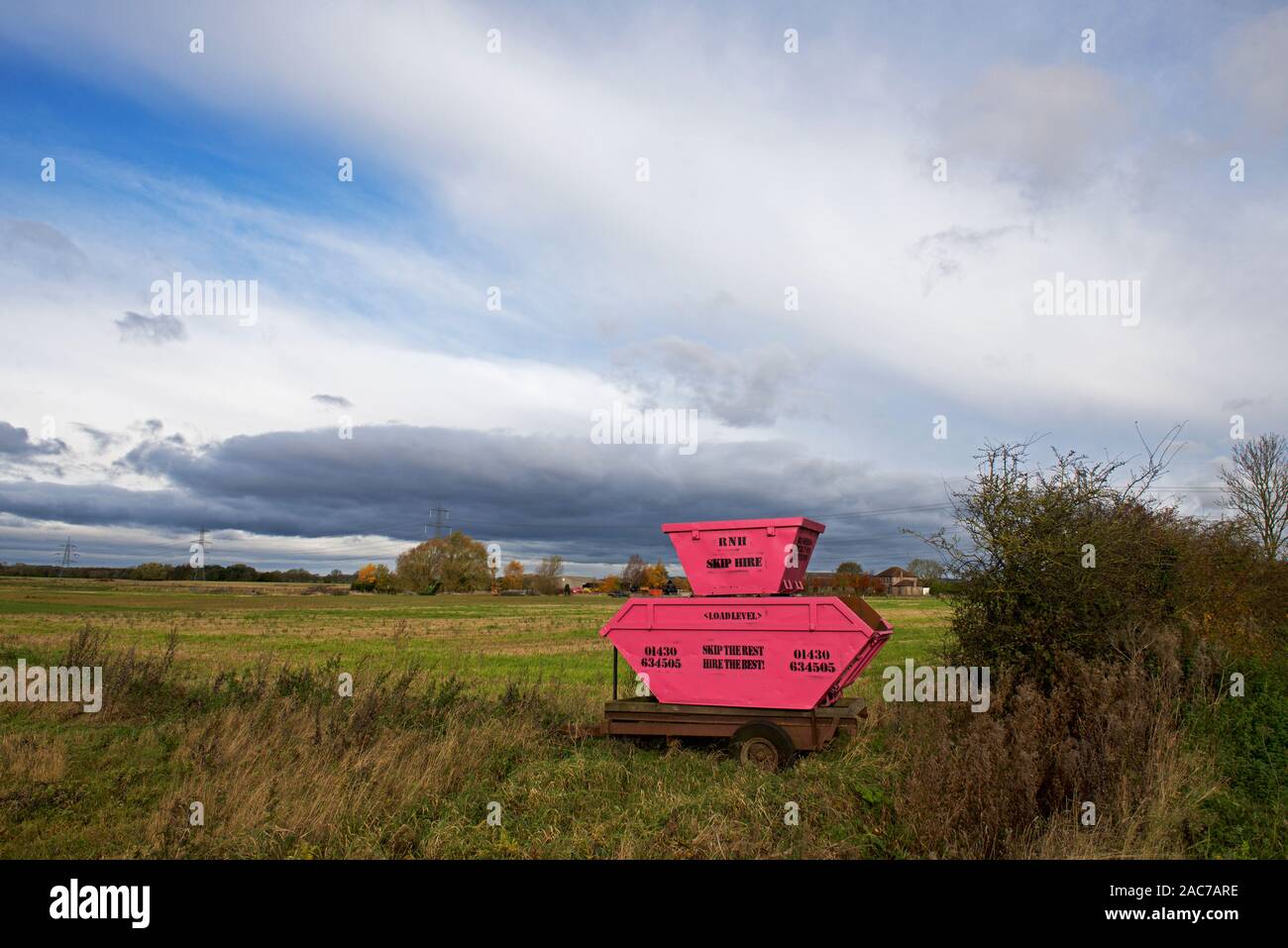 Pink rubbish skips on display in the corner of a field, to advertise a ...