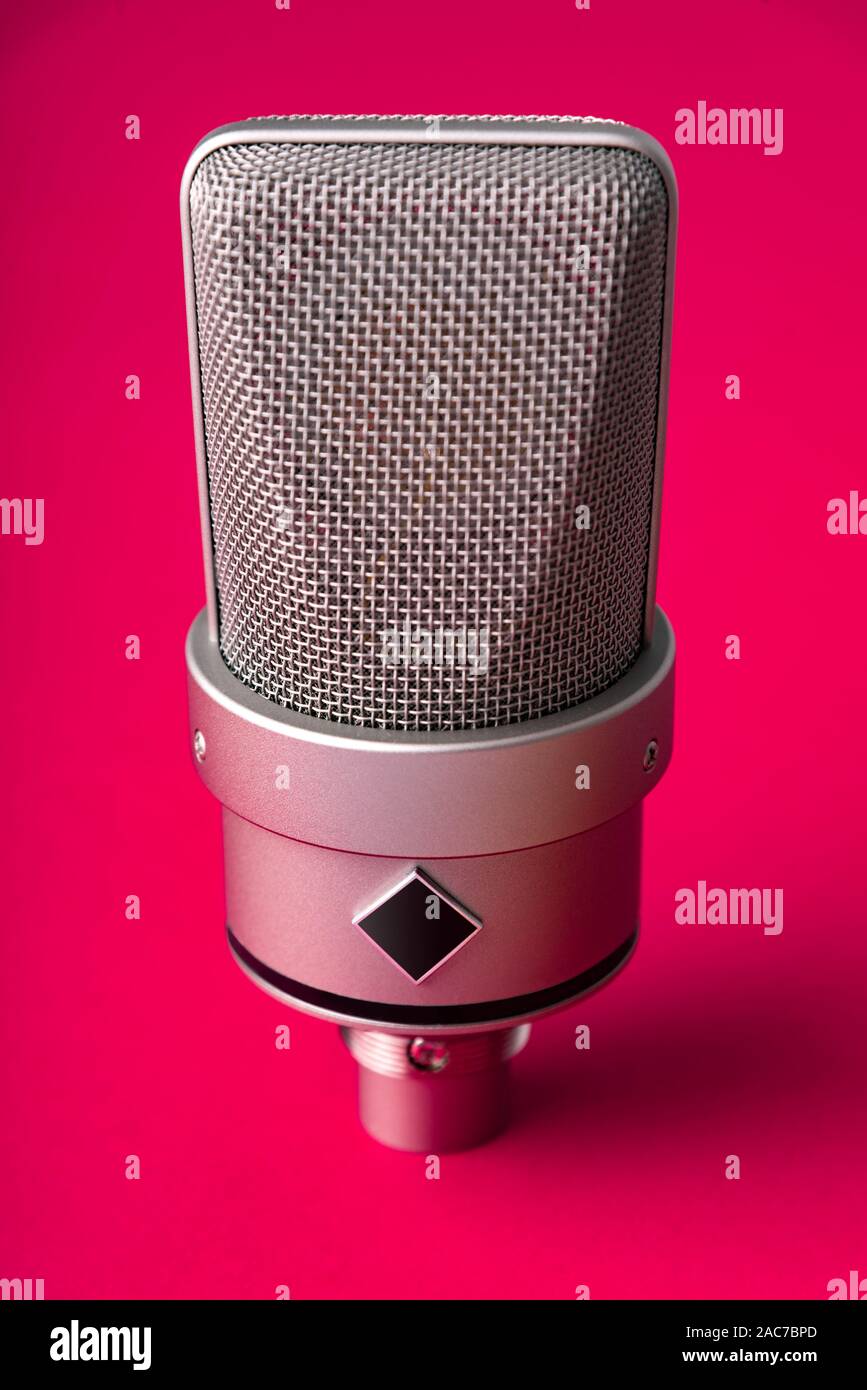 Large diaphragm condenser studio microphone. On a red background Stock ...