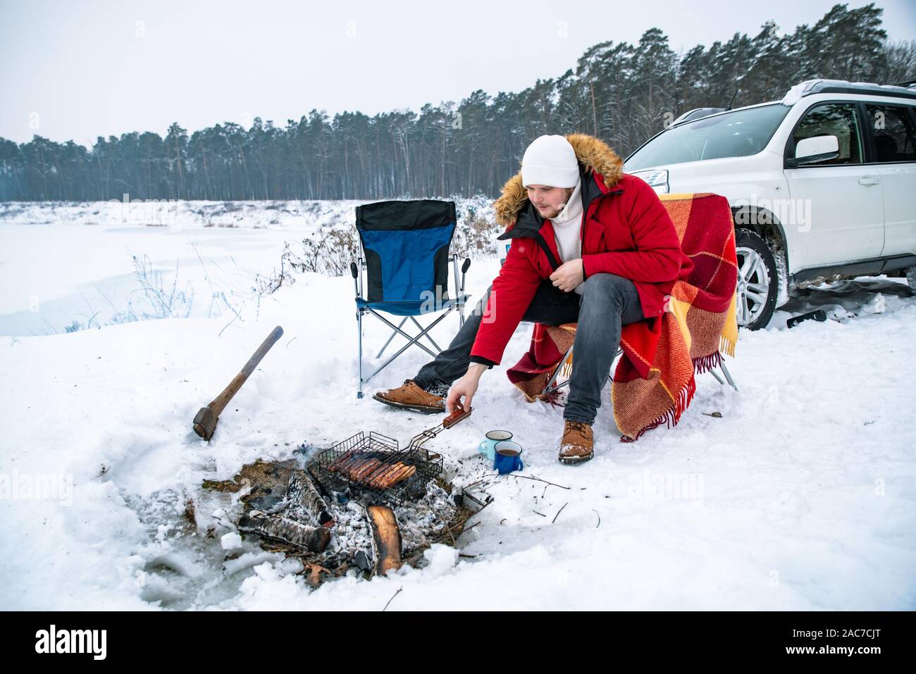 man cooking meat on fire near frozen lake. suv car on background Stock ...