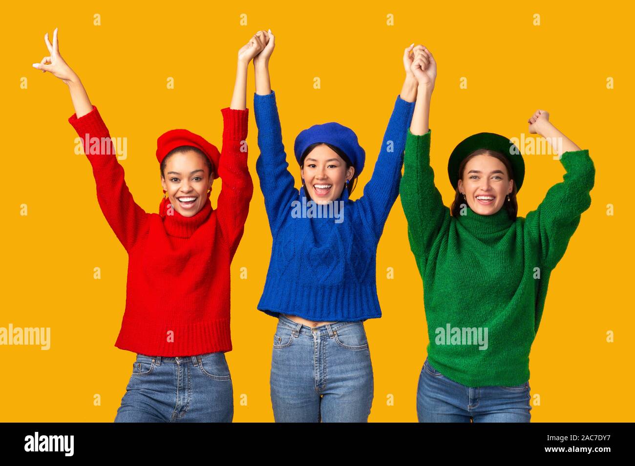Three Happy Girls Holding Raised Hands Standing, Studio Shot Stock ...