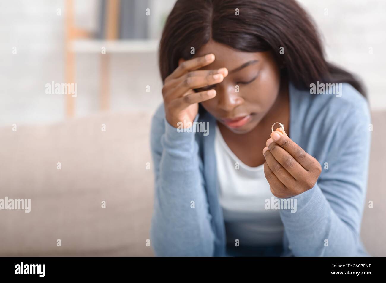 Depressed afro woman holding gold wedding ring, sad about divorce Stock ...