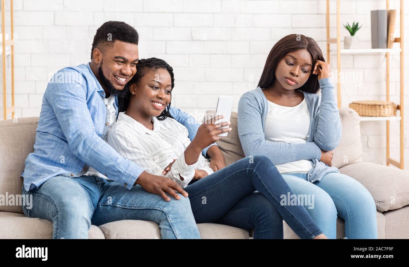 Jealous Black Girl Sitting Near Romantic Couple On Sofa, Feeling Sad ...