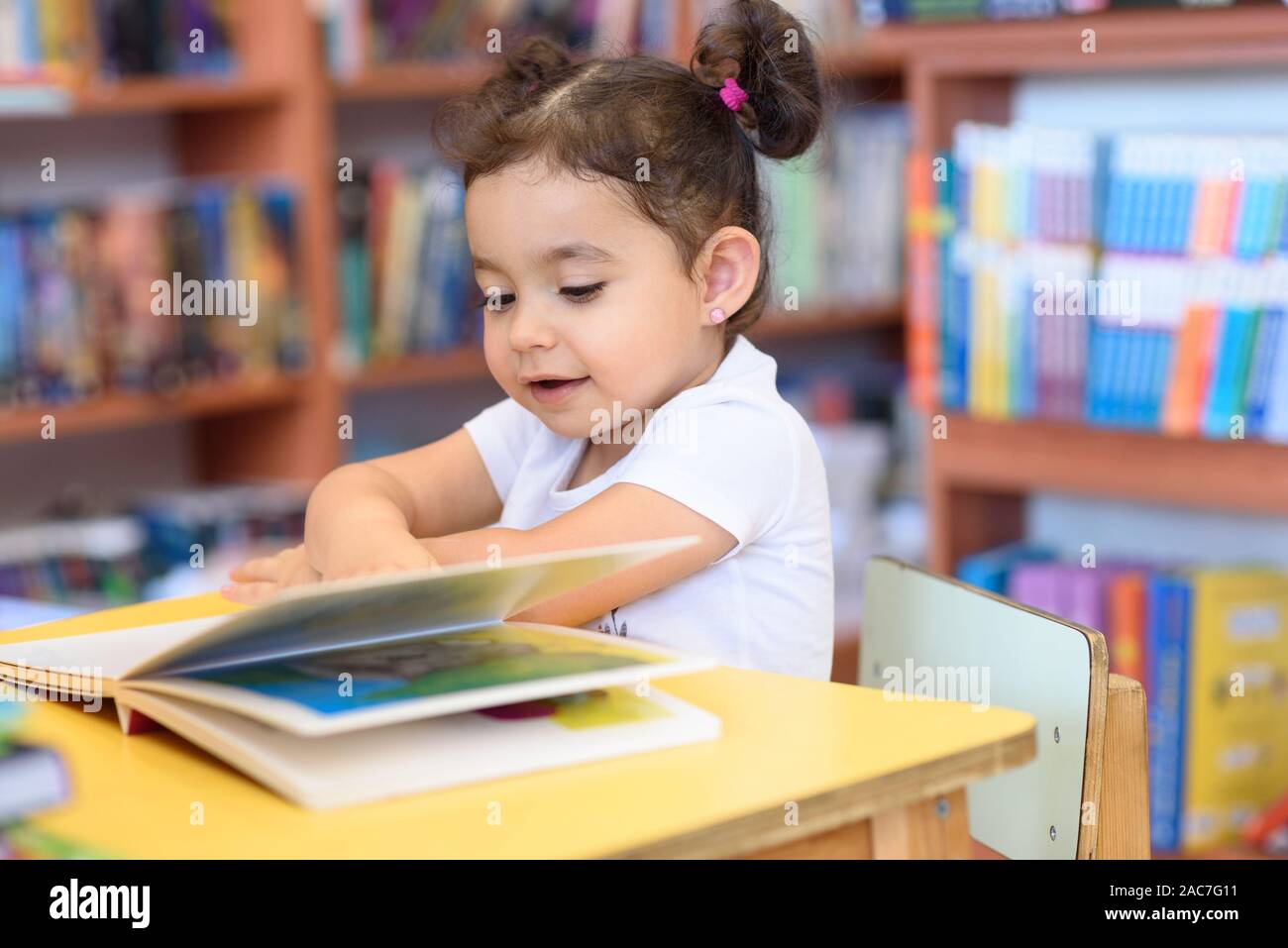 Little Girl Indoors In Front Of Books. Cute Young Toddler Sitting On A ...