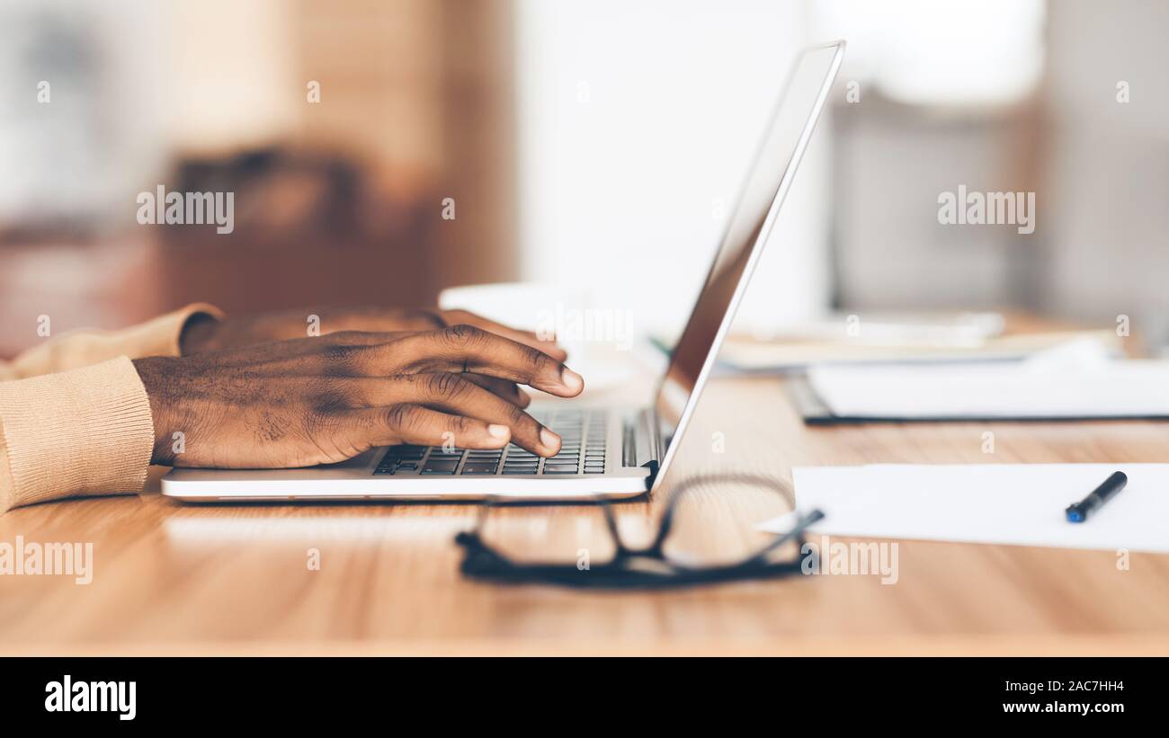 Unrecognizable black guy working on his laptop Stock Photo - Alamy