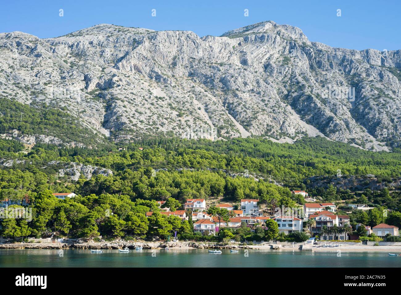 Houses of the city of Orebic on the sandy beach in front of the green ...