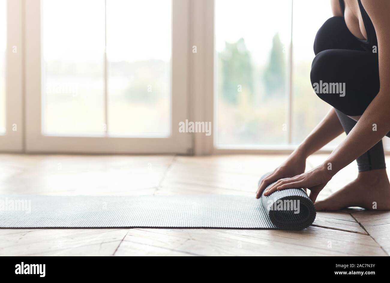 Side view of woman rolling her yoga mat before training Stock Photo - Alamy
