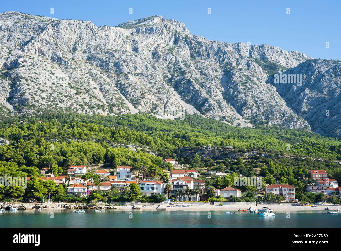Houses of the city of Orebic on the sandy beach in front of the green ...