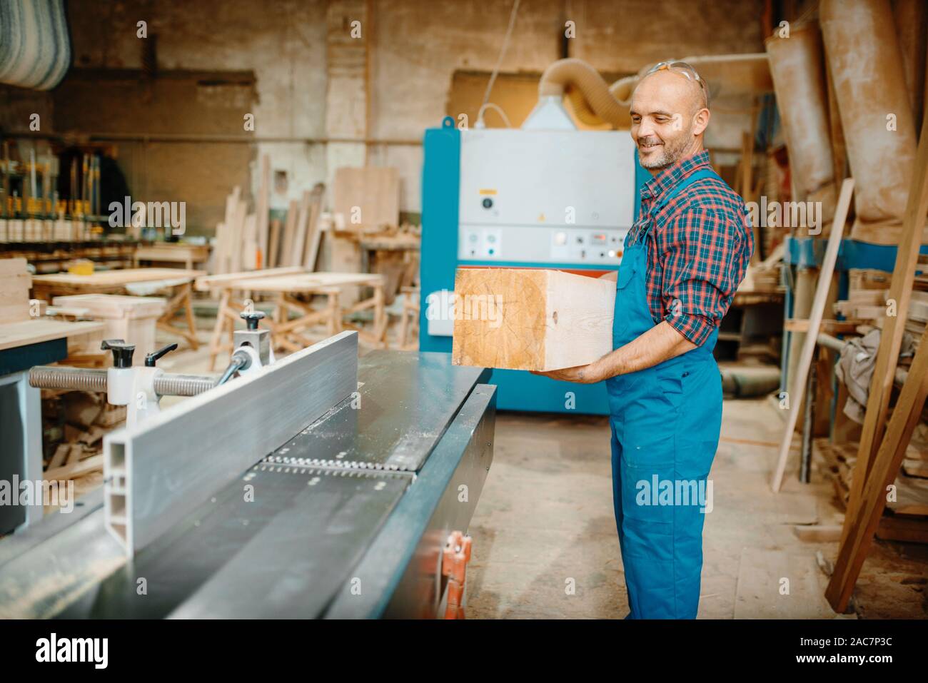 Carpenter processes wooden beam on plane machine Stock Photo - Alamy