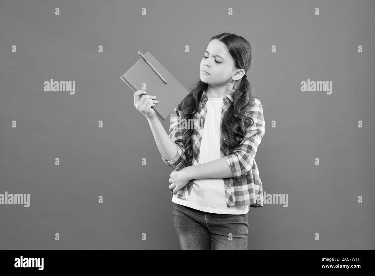 school girl read book on orange background. serious little girl with ...