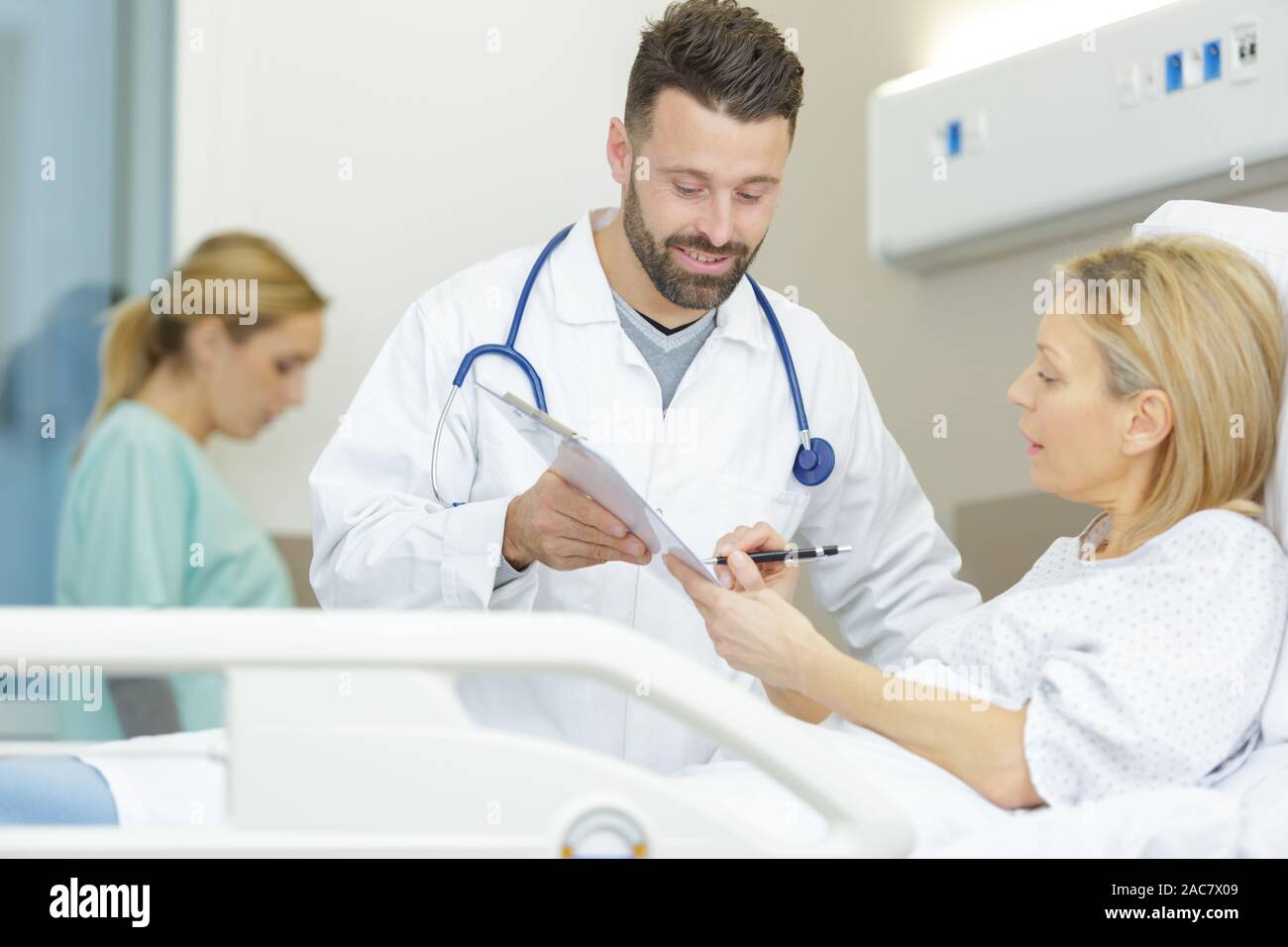 female patient signing paperwork in her hospital bed Stock Photo - Alamy