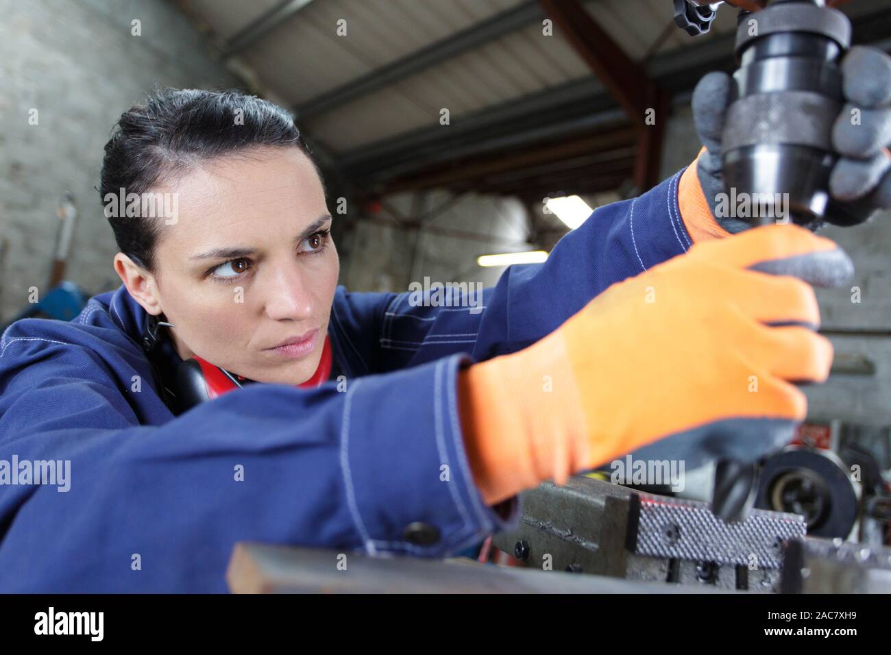female apprentice using drill in factory Stock Photo - Alamy