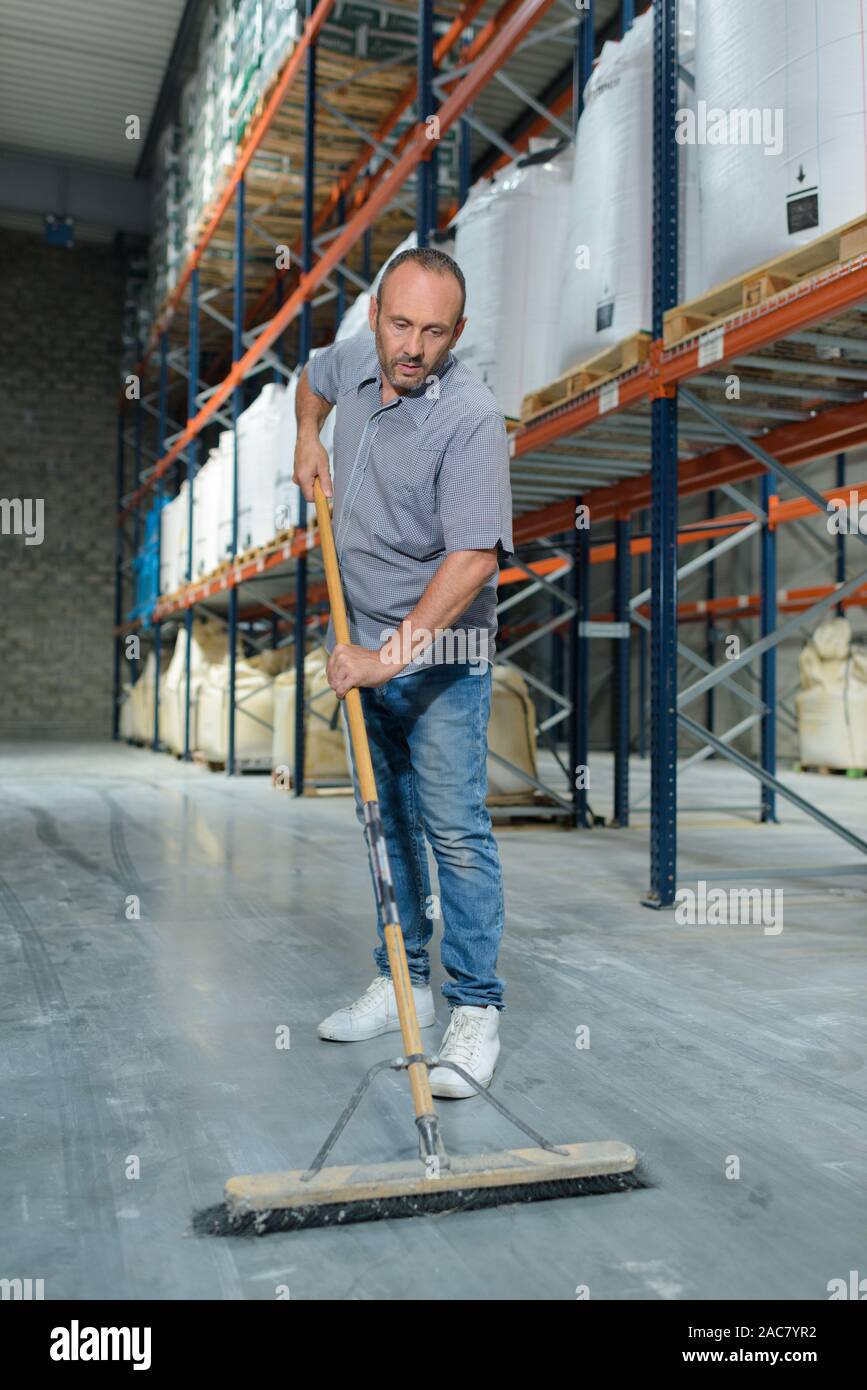 mature man sweeping warehouse floor Stock Photo - Alamy