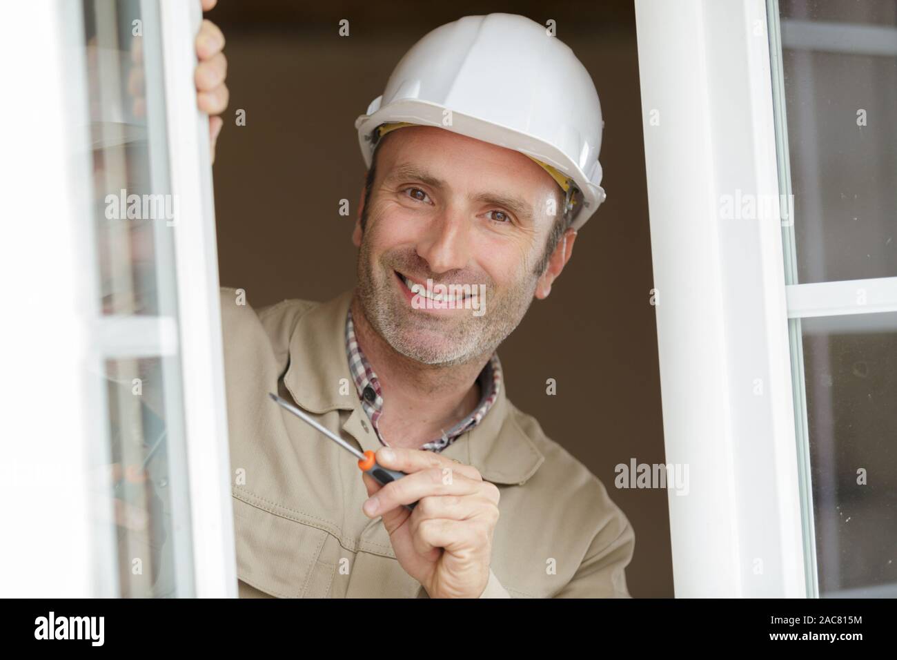 portrait of smiling repairman standing at open window Stock Photo - Alamy