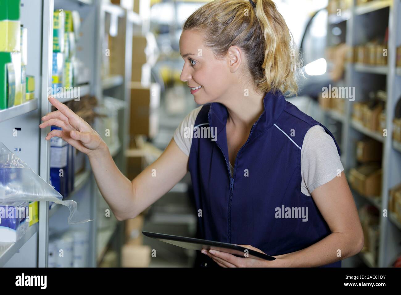 female warehouse worker with tablet selecting stock from racking Stock ...