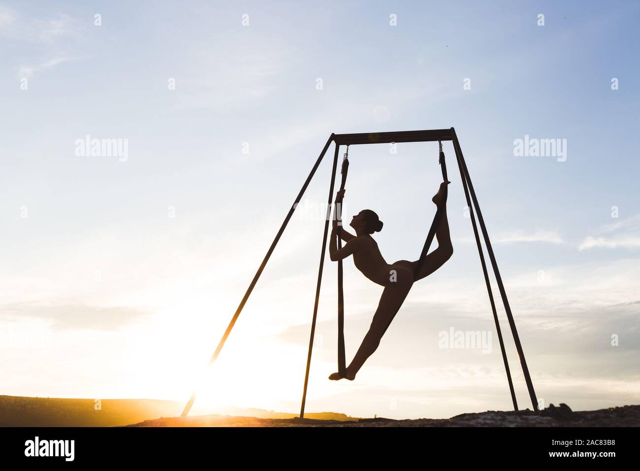 Slim woman practicing fly dance acrobatic yoga poses in hammock ...
