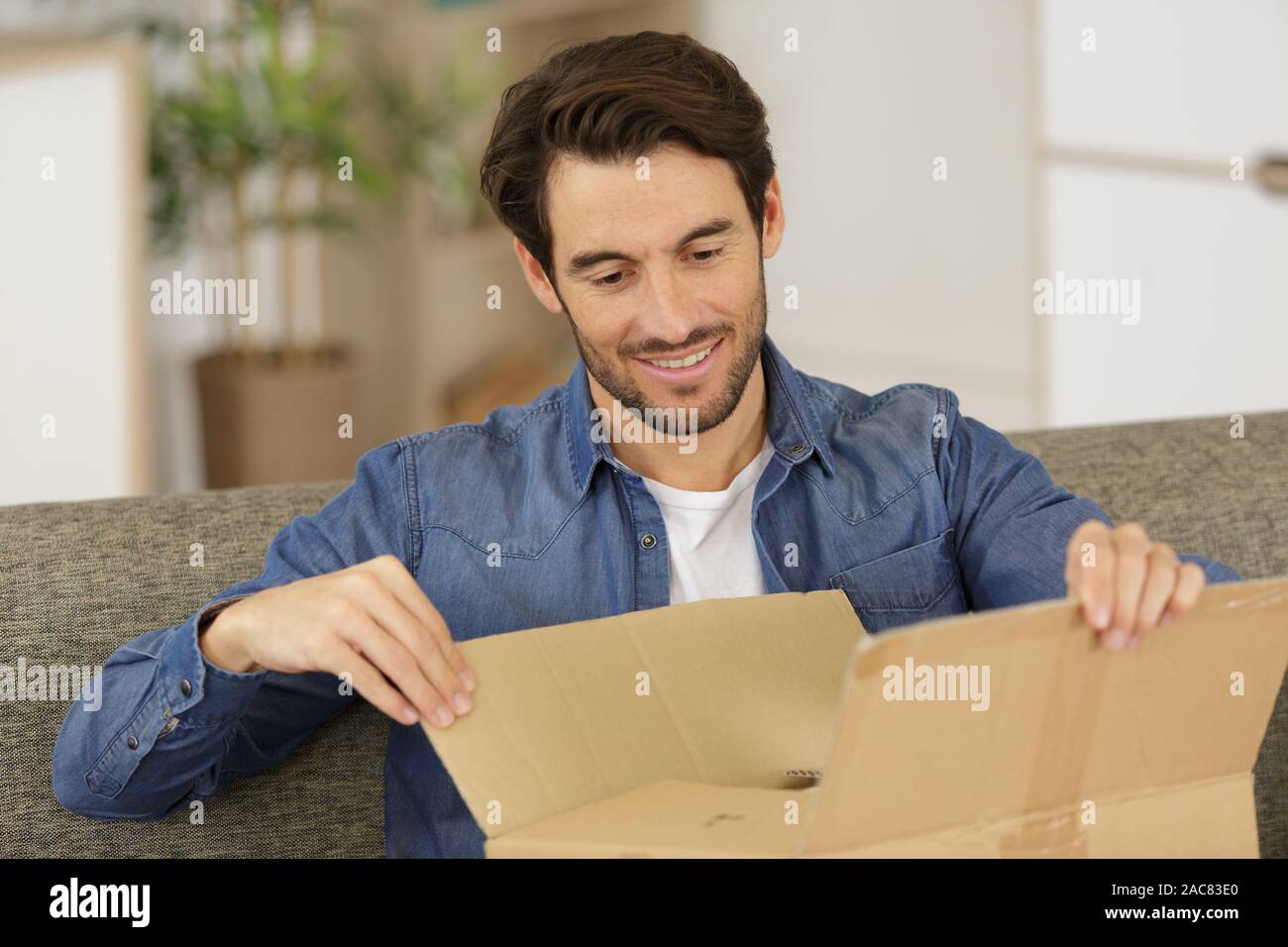 happy man opening parcel box at home Stock Photo - Alamy