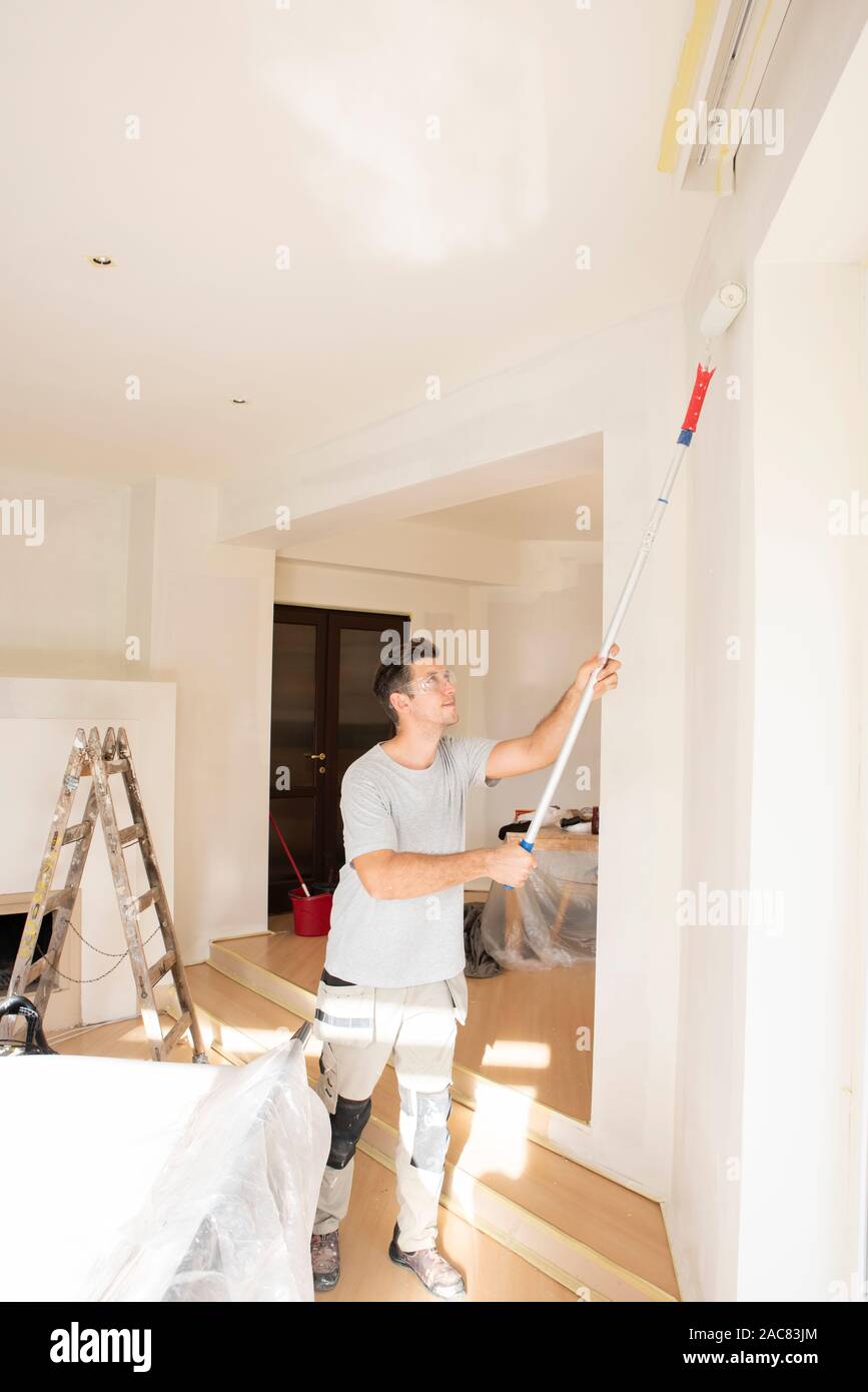Full length shot of young man standing painting the wall in the ...