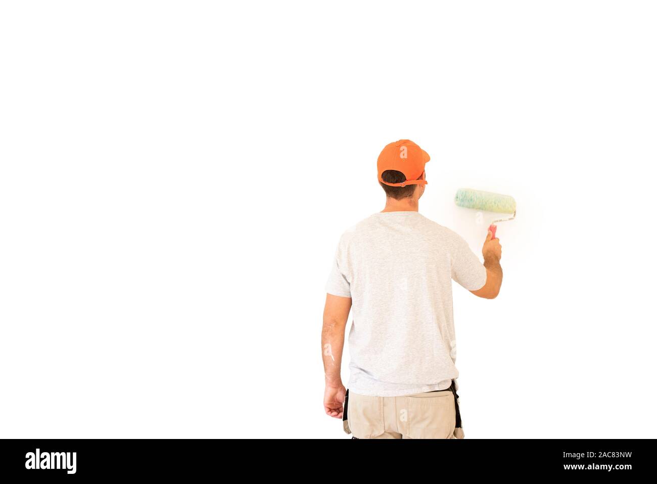 Rear view shot of young man using paint roller while painting white ...