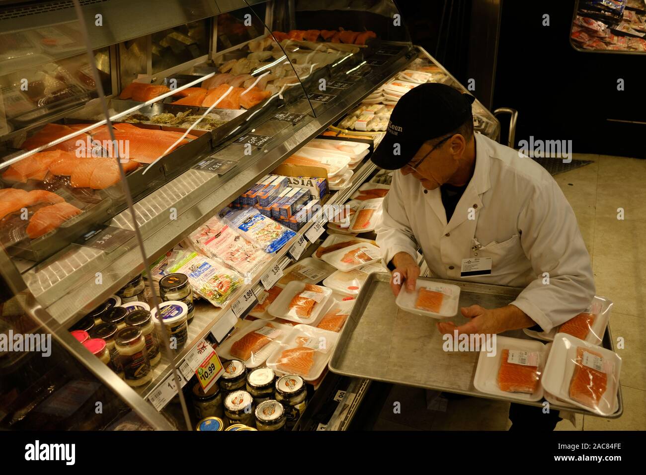 Fishmonger laying out shrink-wrapped fresh fish fillets in the fish ...